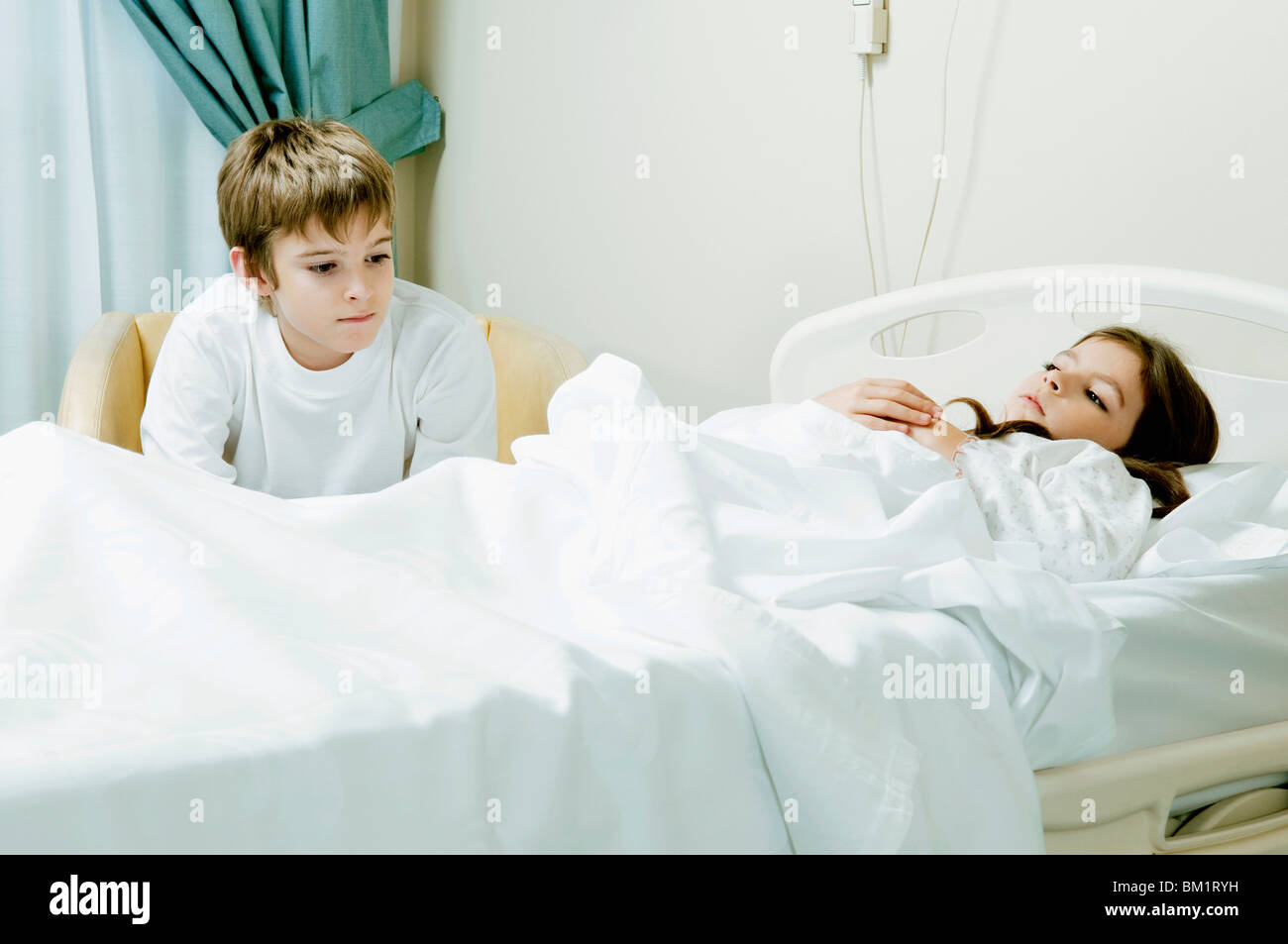 Girl on a hospital bed with her brother sitting beside her Stock Photo ...