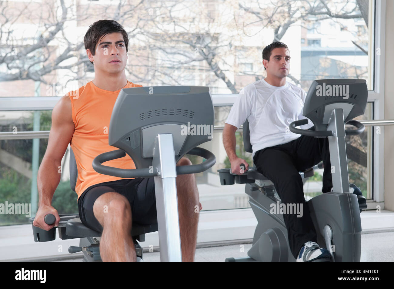 Two men working out on exercise bikes in a gym Stock Photo - Alamy