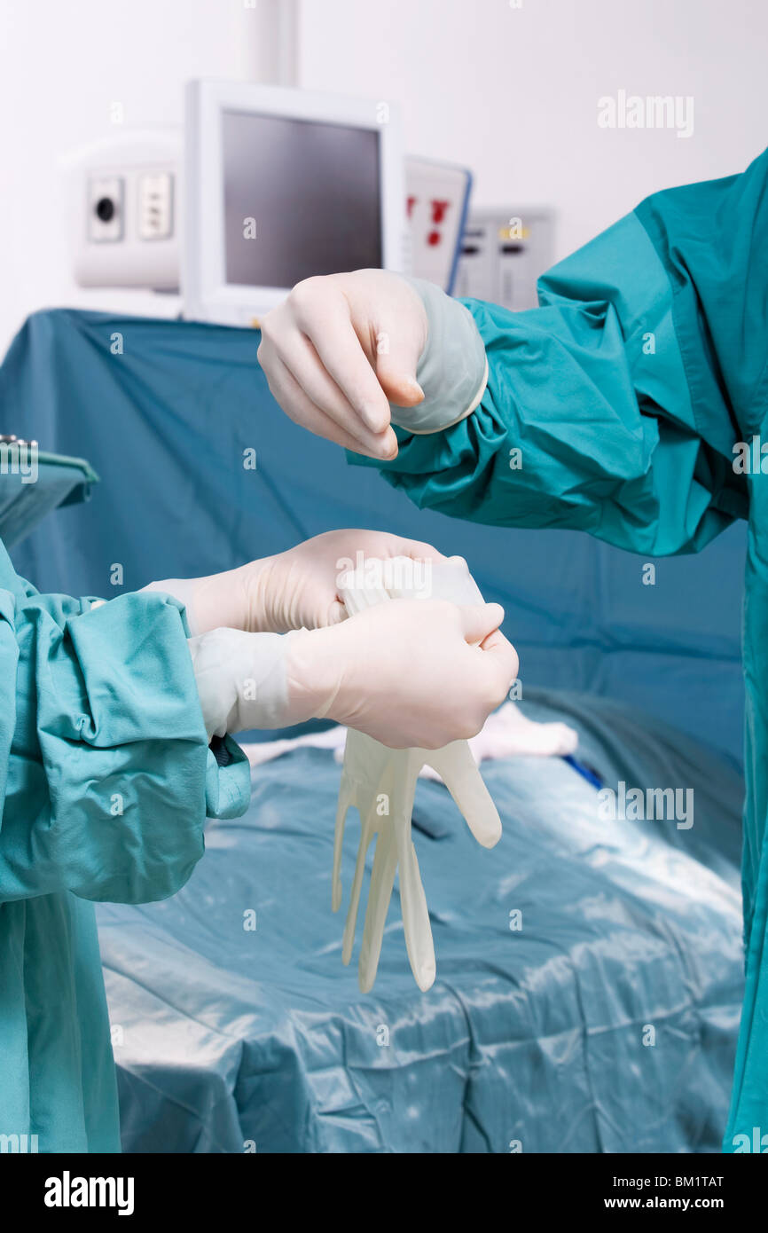 Surgeon putting on surgical gloves Stock Photo - Alamy