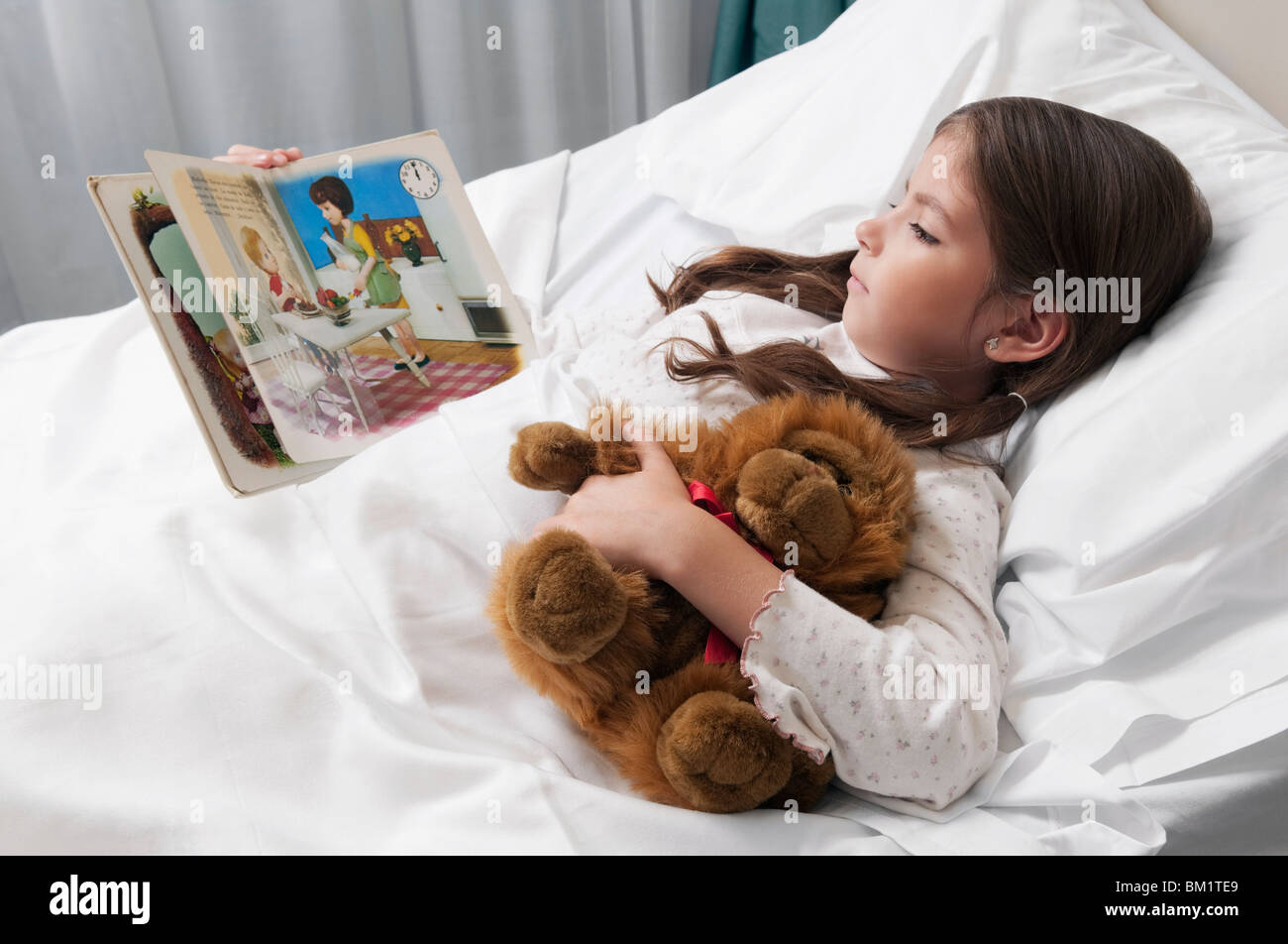 Girl lying in a hospital bed and reading a comic book Stock Photo - Alamy