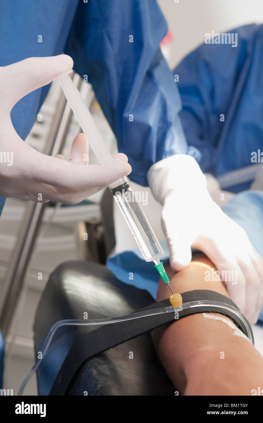 Doctor injecting patient's arm in an operating room Stock Photo - Alamy