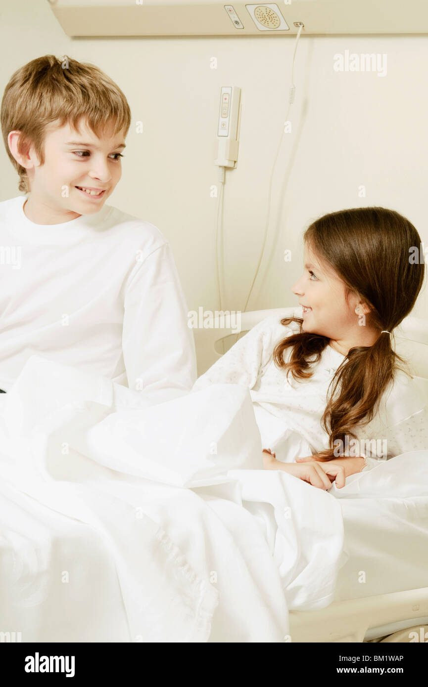 Girl on a hospital bed with her brother sitting beside her Stock Photo ...