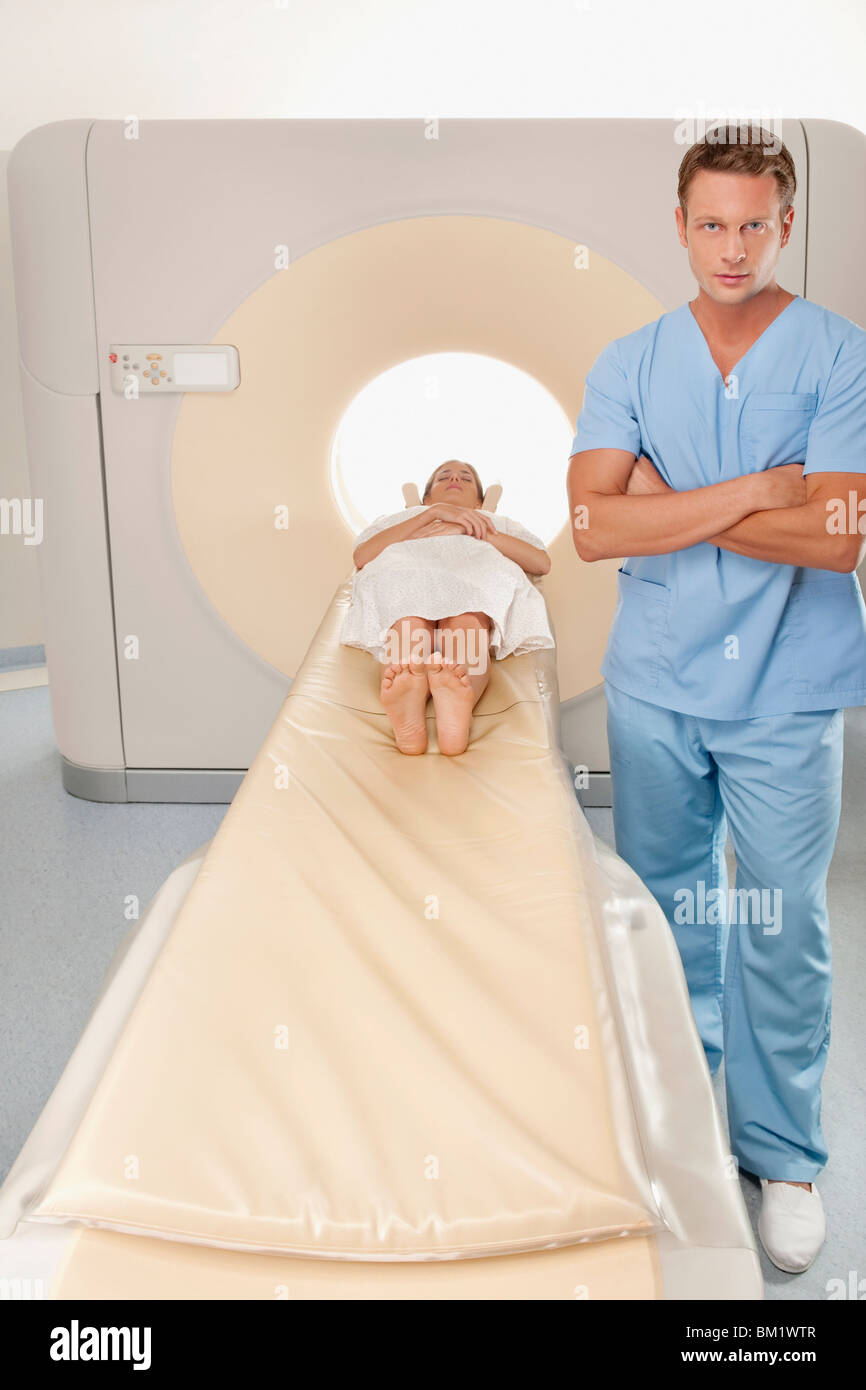 Healthcare worker standing beside a patient undergoing an MRI scan ...