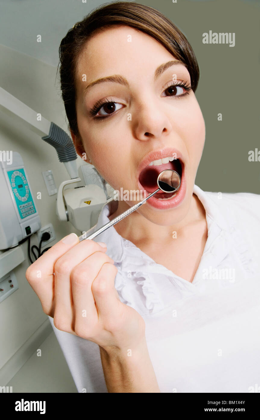 Woman examining her teeth with angled mirror Stock Photo - Alamy
