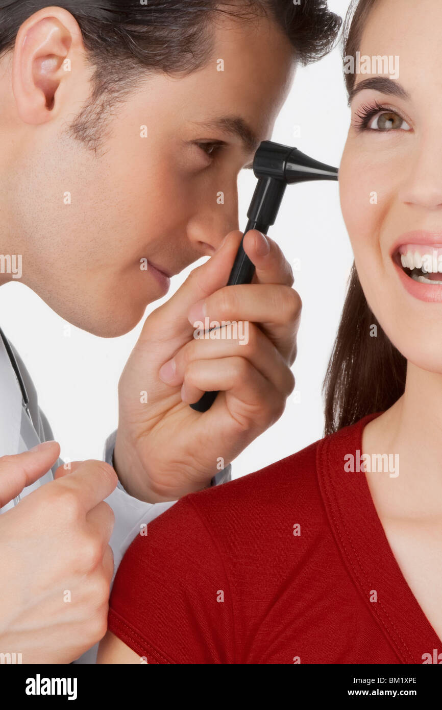 Doctor examining a woman's ear with an otoscope Stock Photo - Alamy