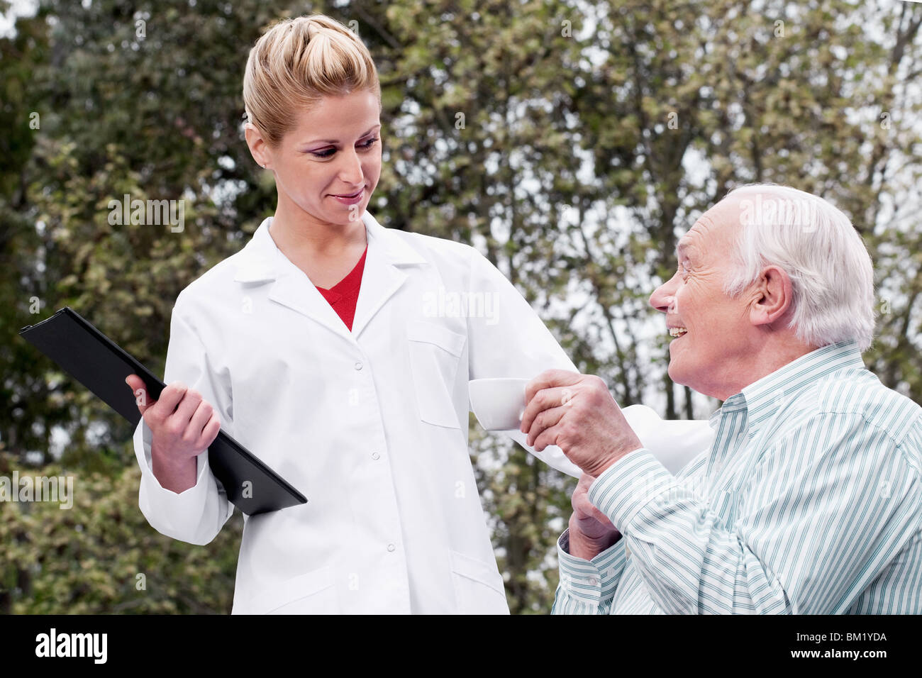 Man drinking tea with a doctor standing beside him Stock Photo - Alamy