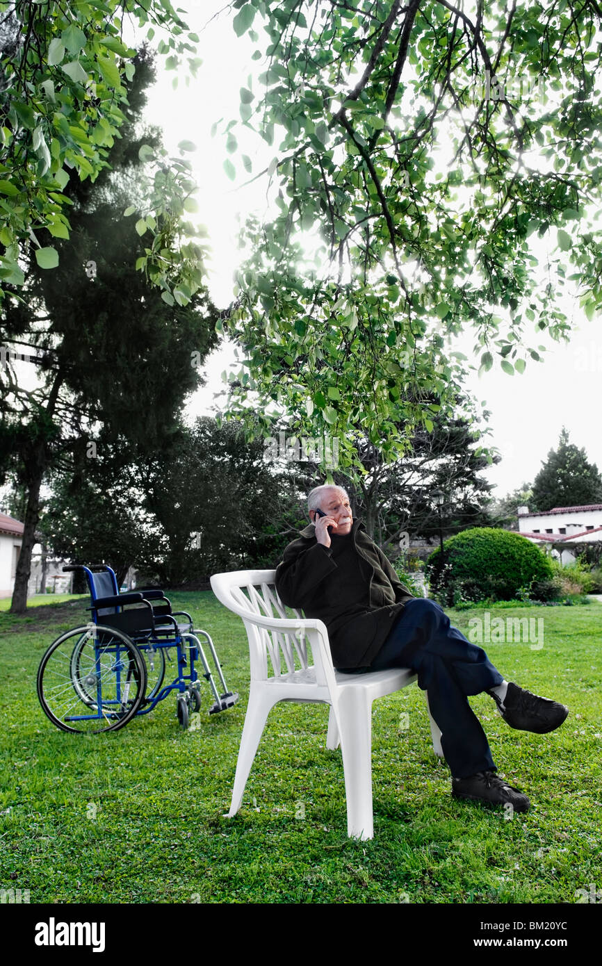 Man sitting on a chair and talking on a mobile phone Stock Photo - Alamy