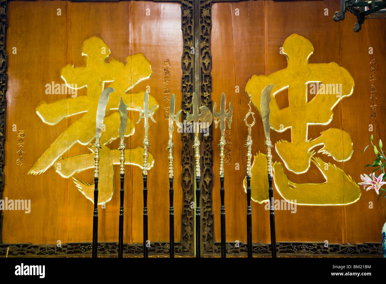 Symbolic weapons by a wooden wall with Chinese characters on inside ...