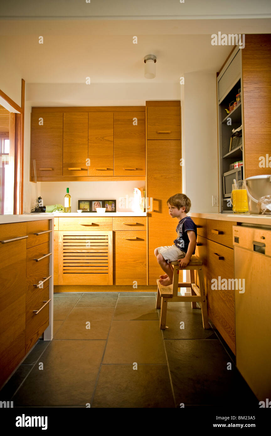 Boy sitting on a stool in the kitchen, La Jolla, California, USA Stock ...