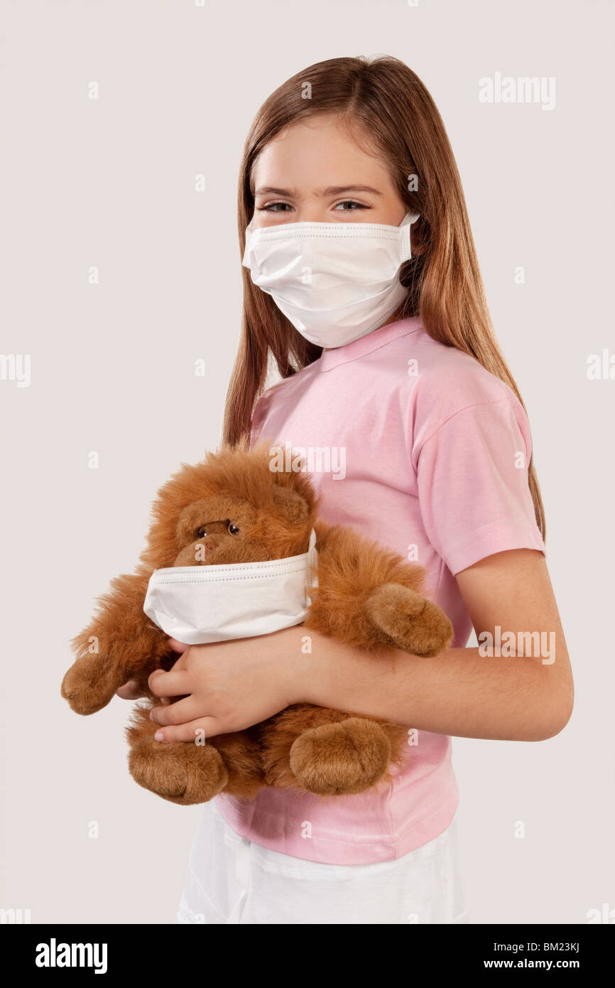 Girl wearing flu mask and holding a teddy bear Stock Photo - Alamy