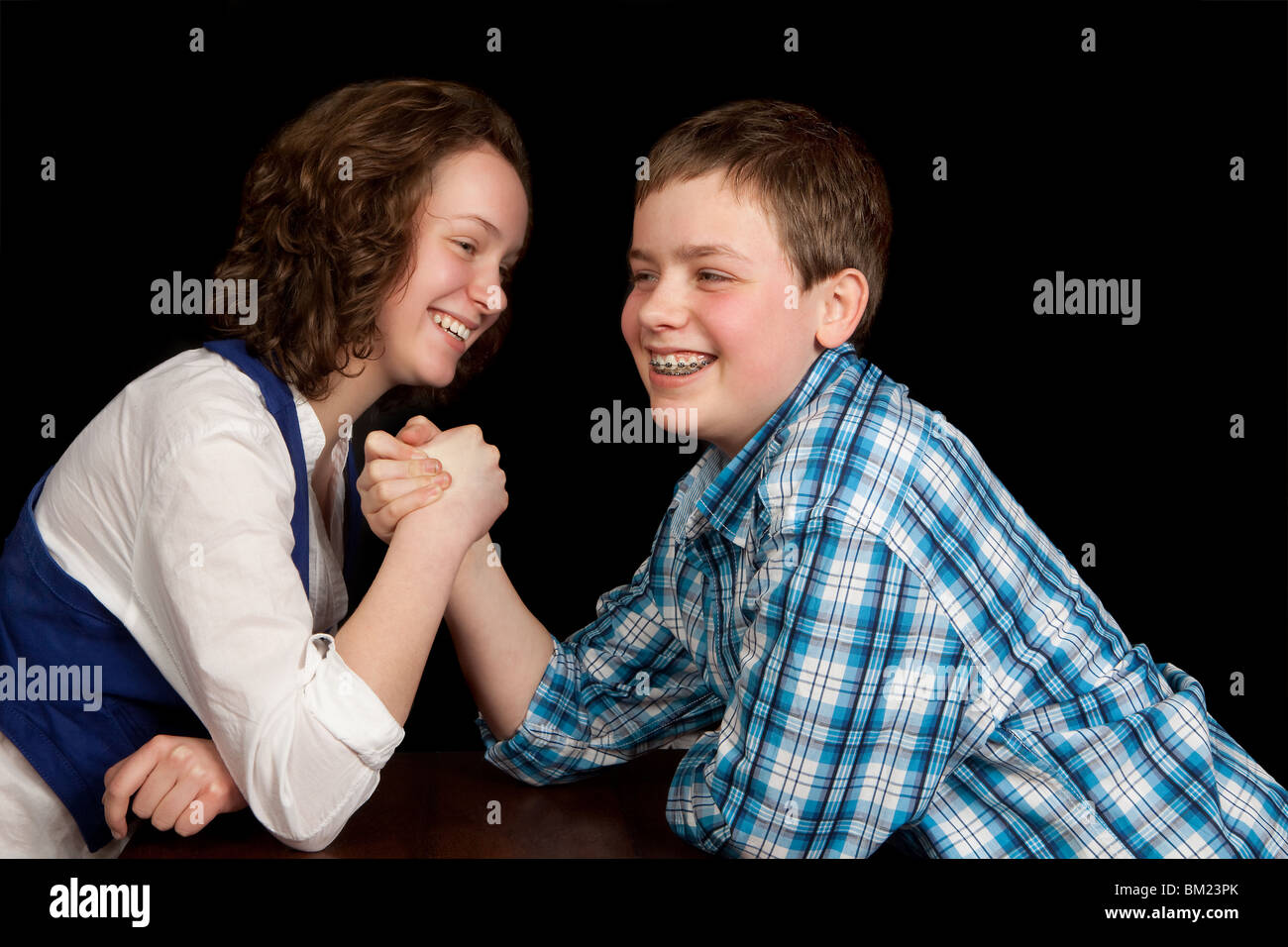 Caucasian teenager boy and girl enjoying an arm-wrestling challenge ...