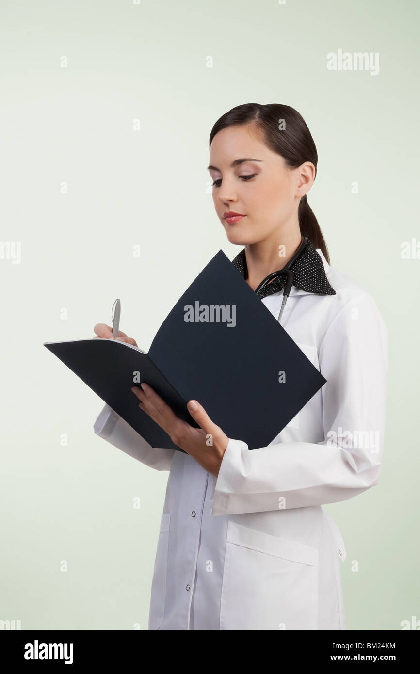 Female doctor writing in a file Stock Photo - Alamy