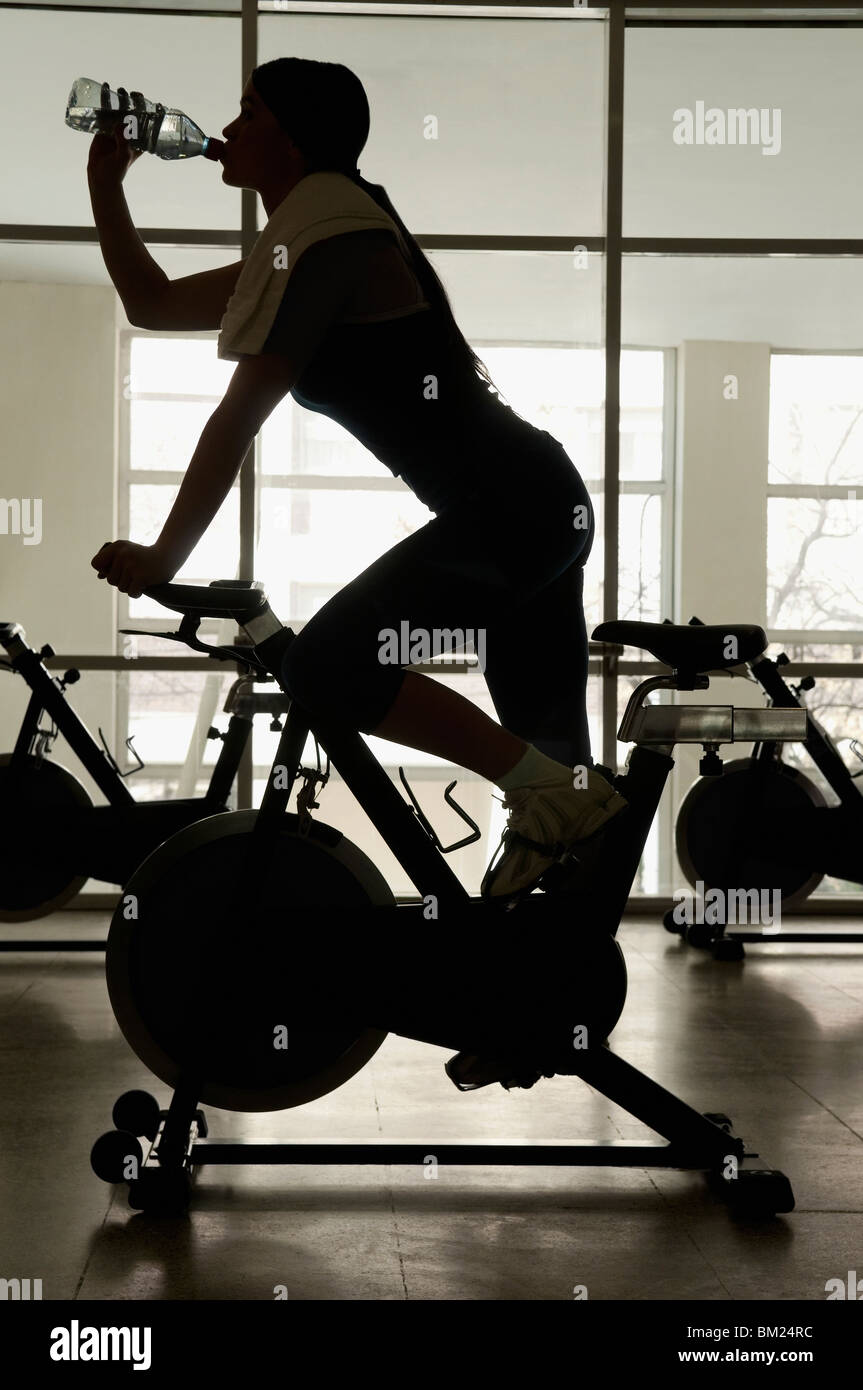 Silhouette of a woman drinking water and working out on an exercise ...