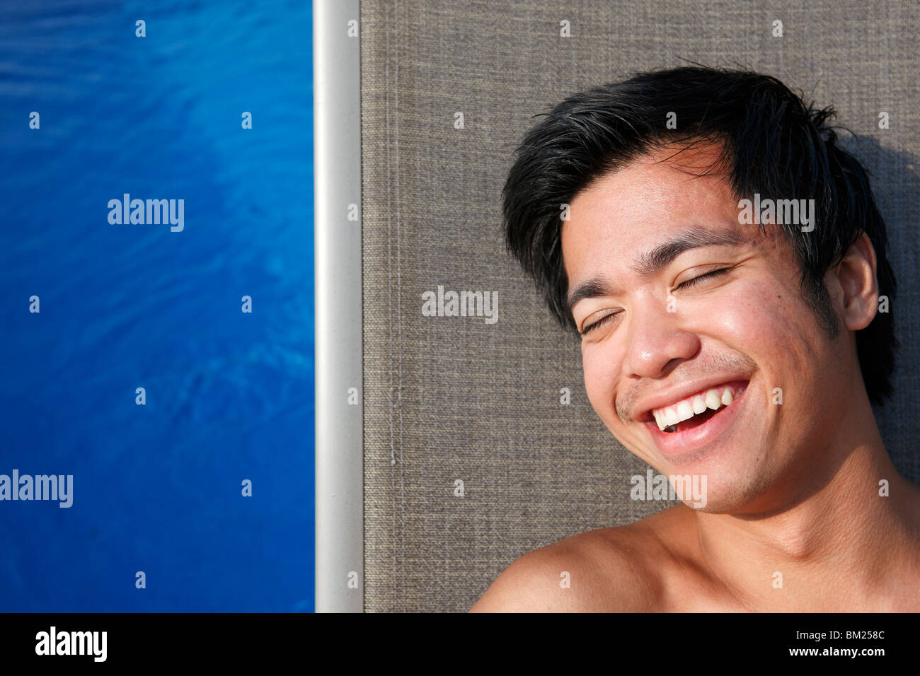 Young man lying on a lounge chair and smiling Stock Photo - Alamy