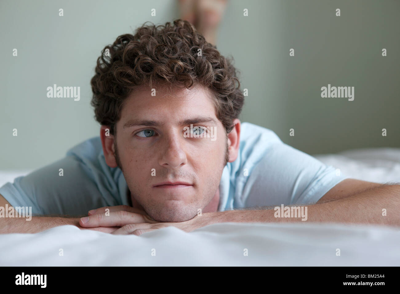 Young man lying on the bed and thinking Stock Photo - Alamy