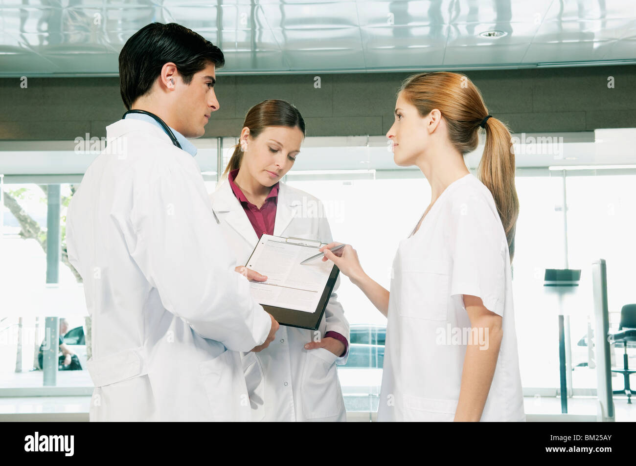 Three doctors discussing a report Stock Photo - Alamy