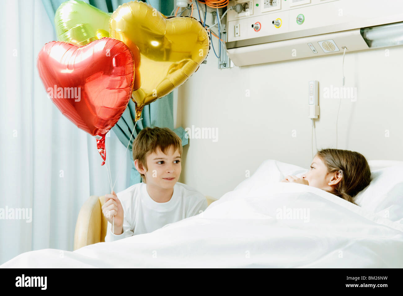 Girl on a hospital bed with her brother holding balloons Stock Photo ...