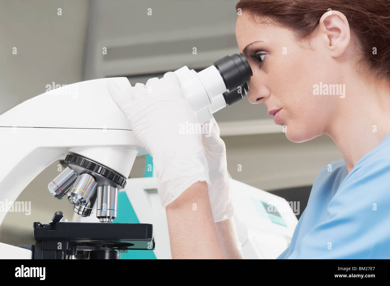 Female lab technician analyzing a sample through a microscope Stock ...
