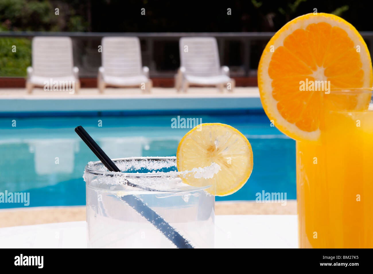 Lounge chairs with juices on table at the poolside Stock Photo - Alamy