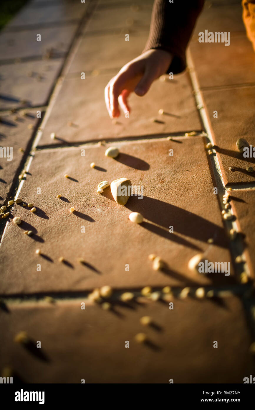 Child's hand picking up pebbles from the floor, Seville, Spain Stock ...