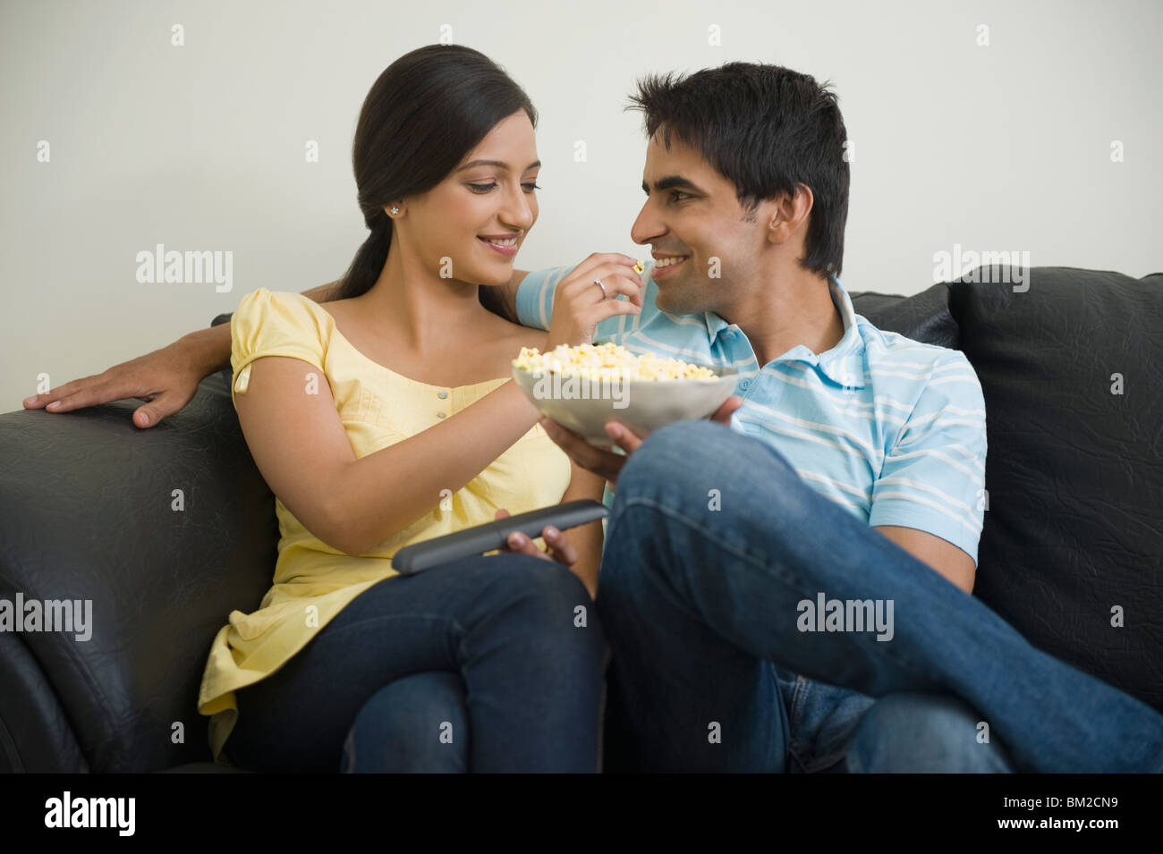 Couple smiling and eating popcorn Stock Photo - Alamy