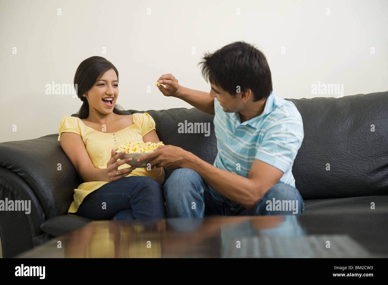 Couple smiling and eating popcorn Stock Photo - Alamy
