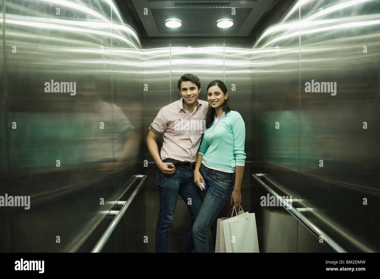 Couple carrying shopping bags in an elevator Stock Photo - Alamy