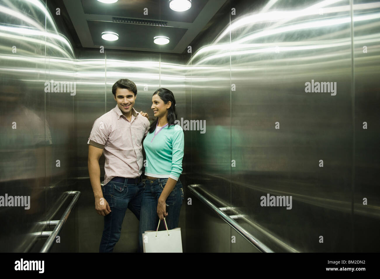 Couple carrying shopping bags in an elevator Stock Photo - Alamy