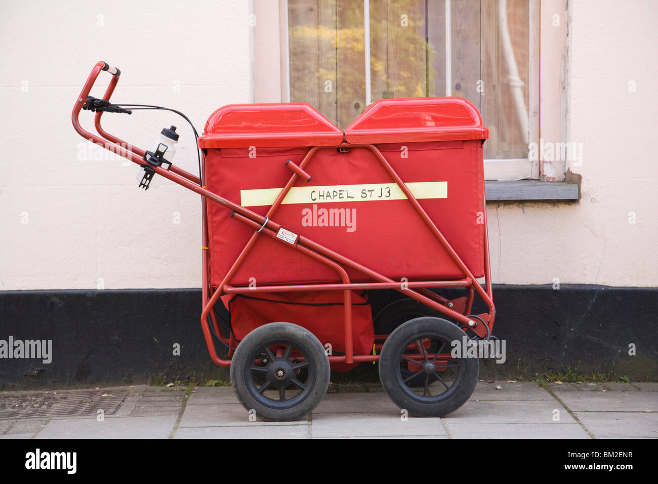 A red postman's delivery trolley awaits his return, England Stock Photo ...