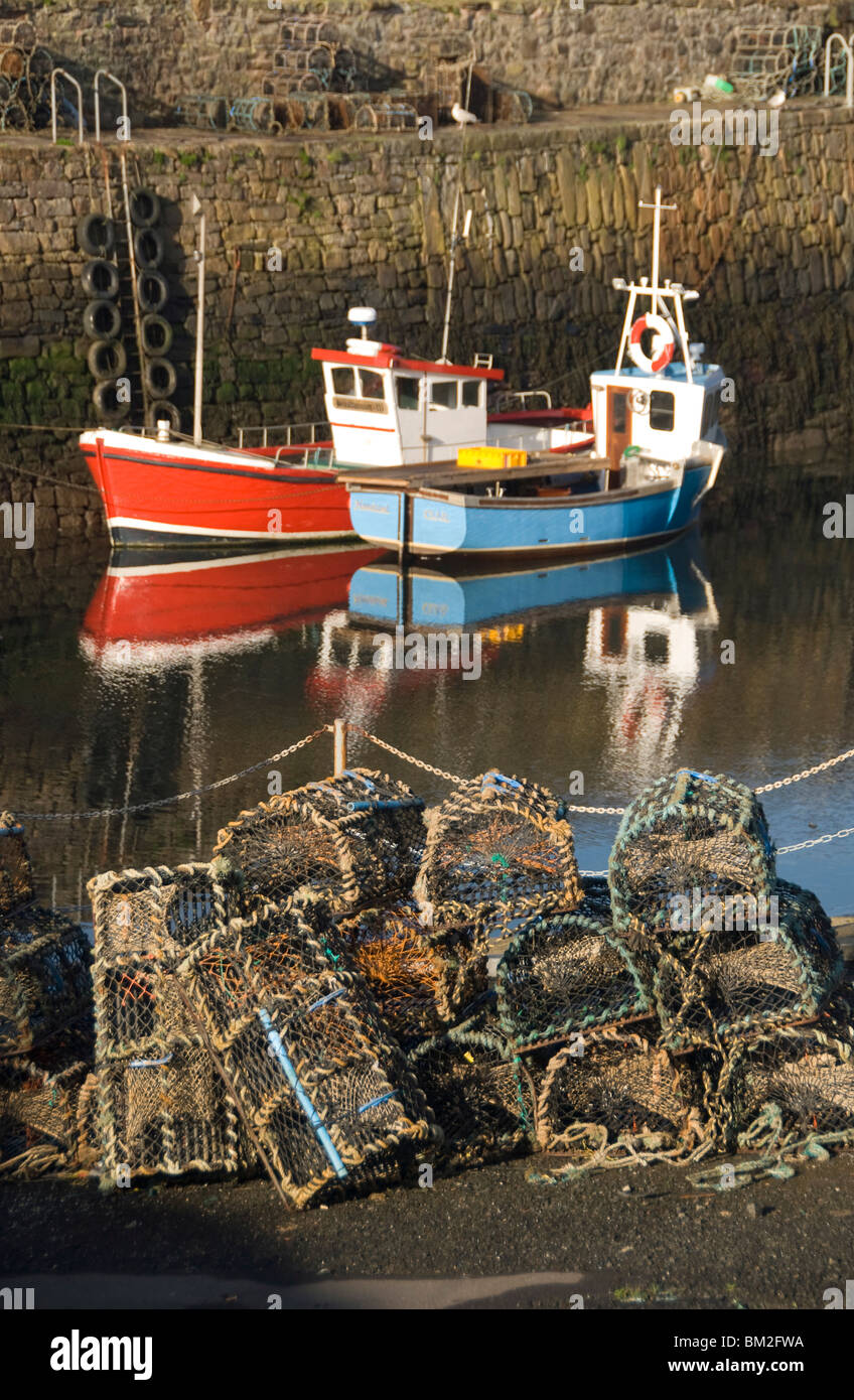 Lobster creels in the foreground with fishing boats in the harbour ...