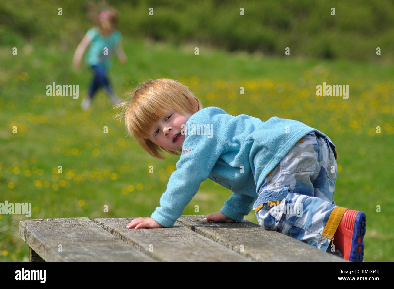 Boy age 2 climbing on pub picnic table Stock Photo - Alamy