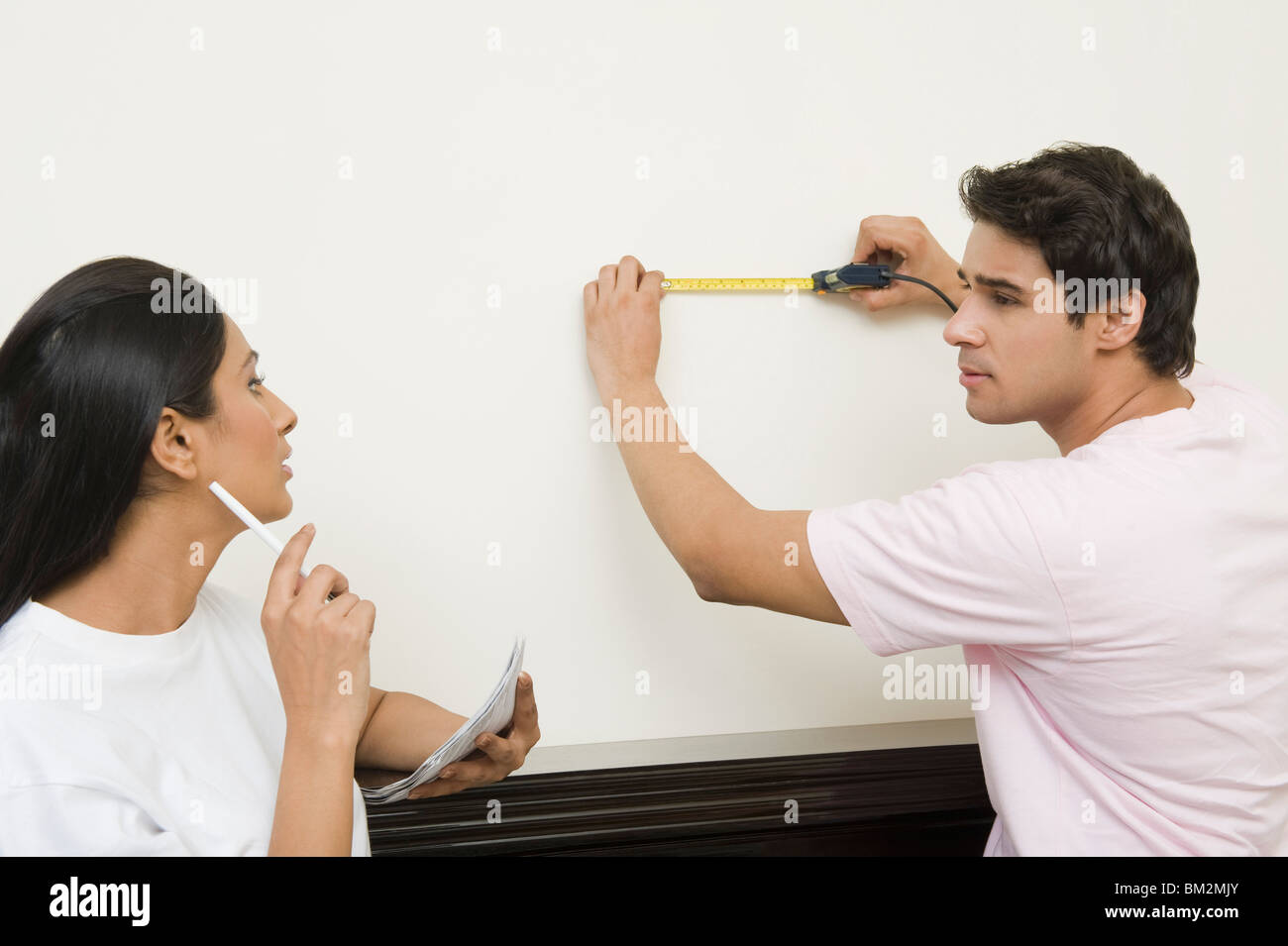 Couple measuring the wall with a tape measure Stock Photo - Alamy