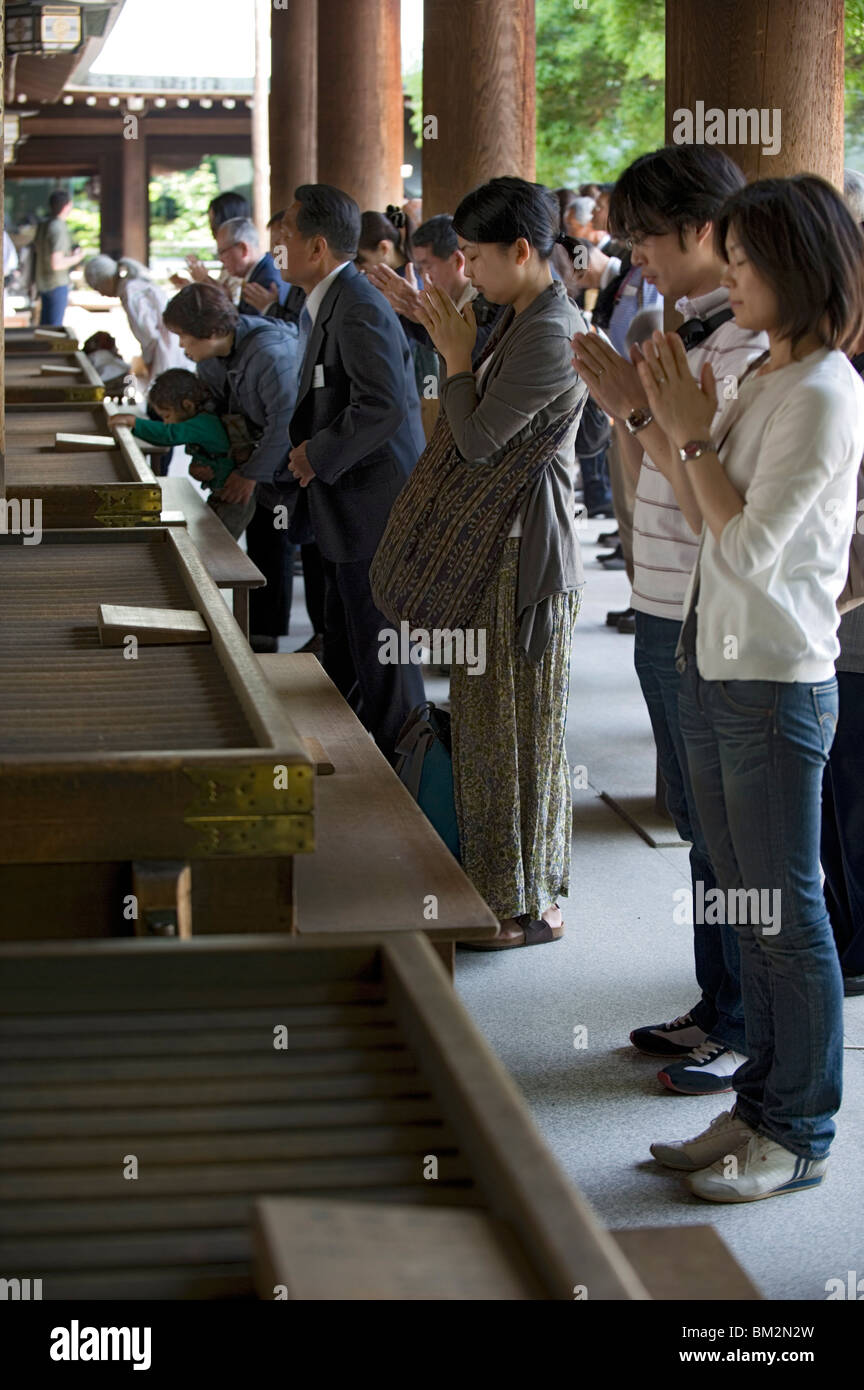 Worshippers praying in front of offertory boxes at main hall of Meiji ...