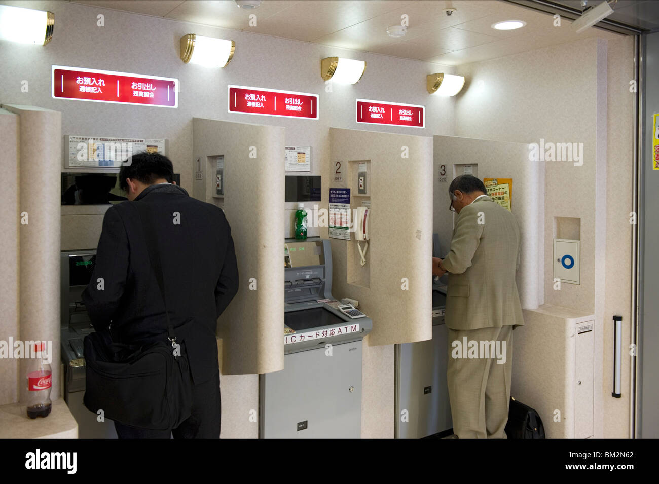 People doing after-hours banking at bank teller machines in Japan Stock ...