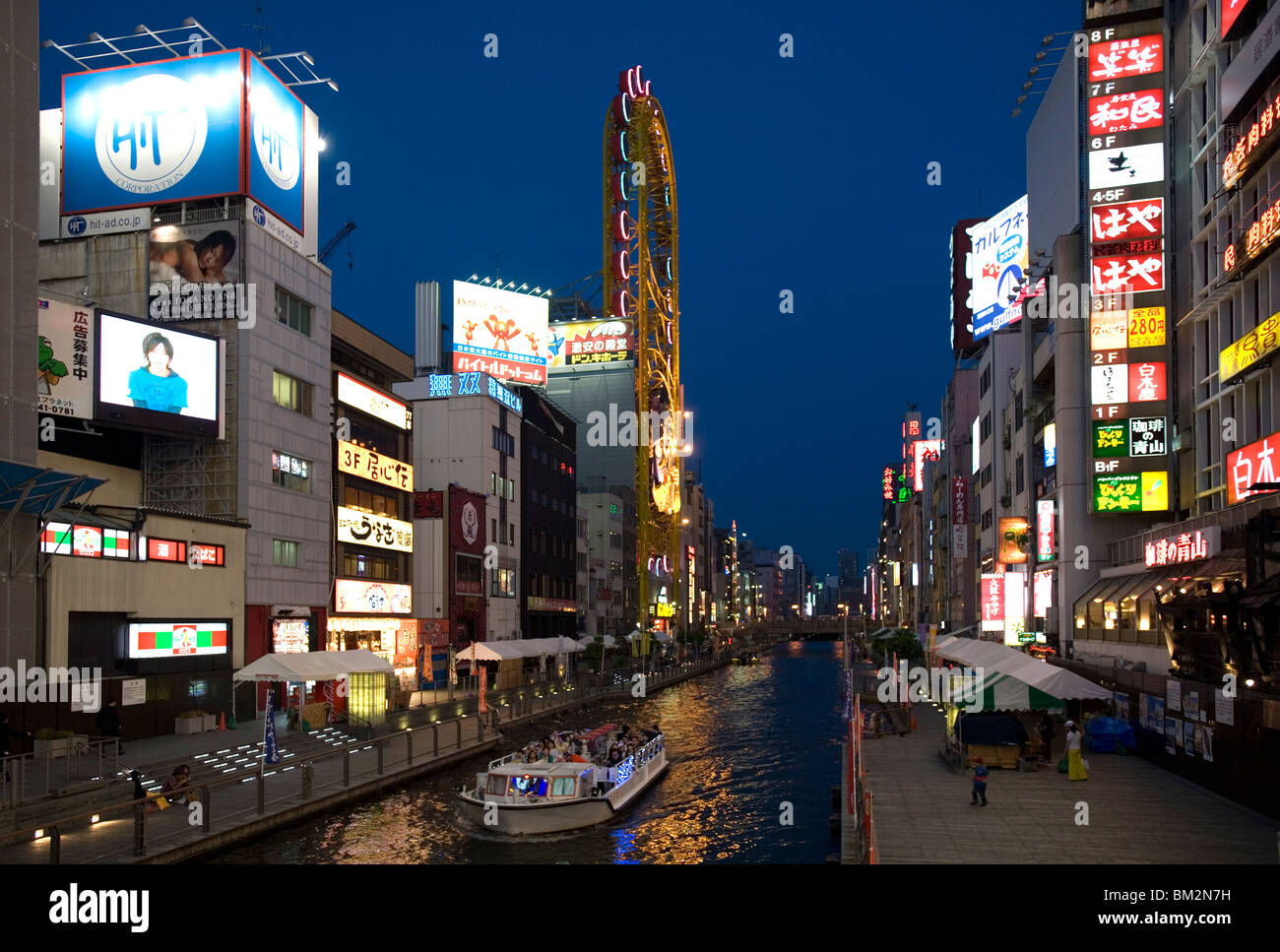 Tour boat on Dotonbori River glides past shops and restaurants in Namba ...