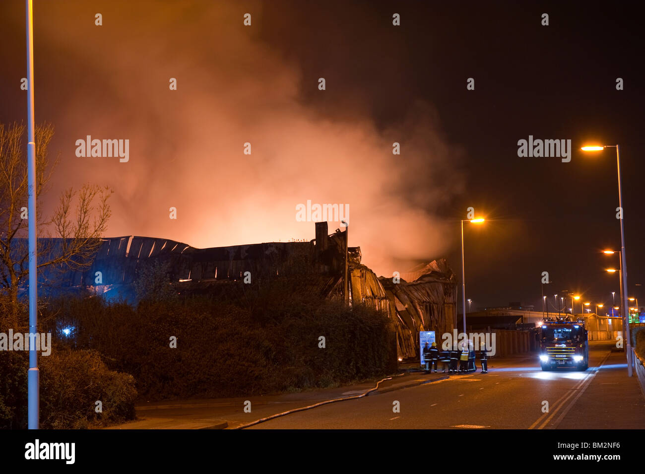 Large factory warehouse on fire at night with lots of flames and smoke ...