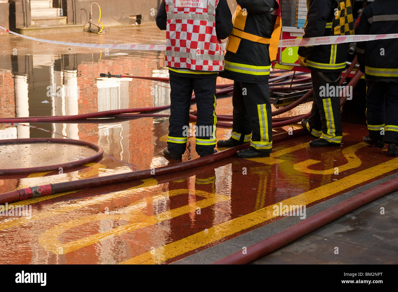 Firemen standing in run off water at large fire Stock Photo - Alamy