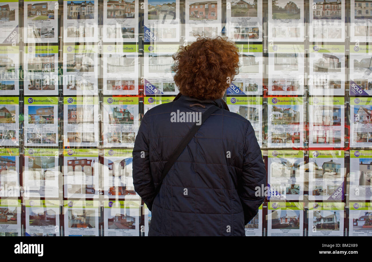 Woman viewing properties in estate agency window Stock Photo - Alamy
