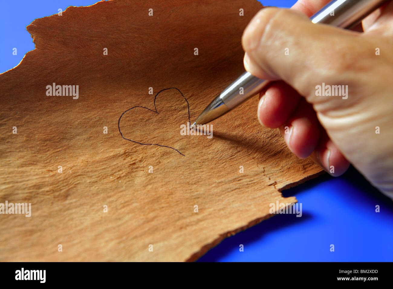 Human hand writing, drawing with a pen a heart on wood, valentines day ...