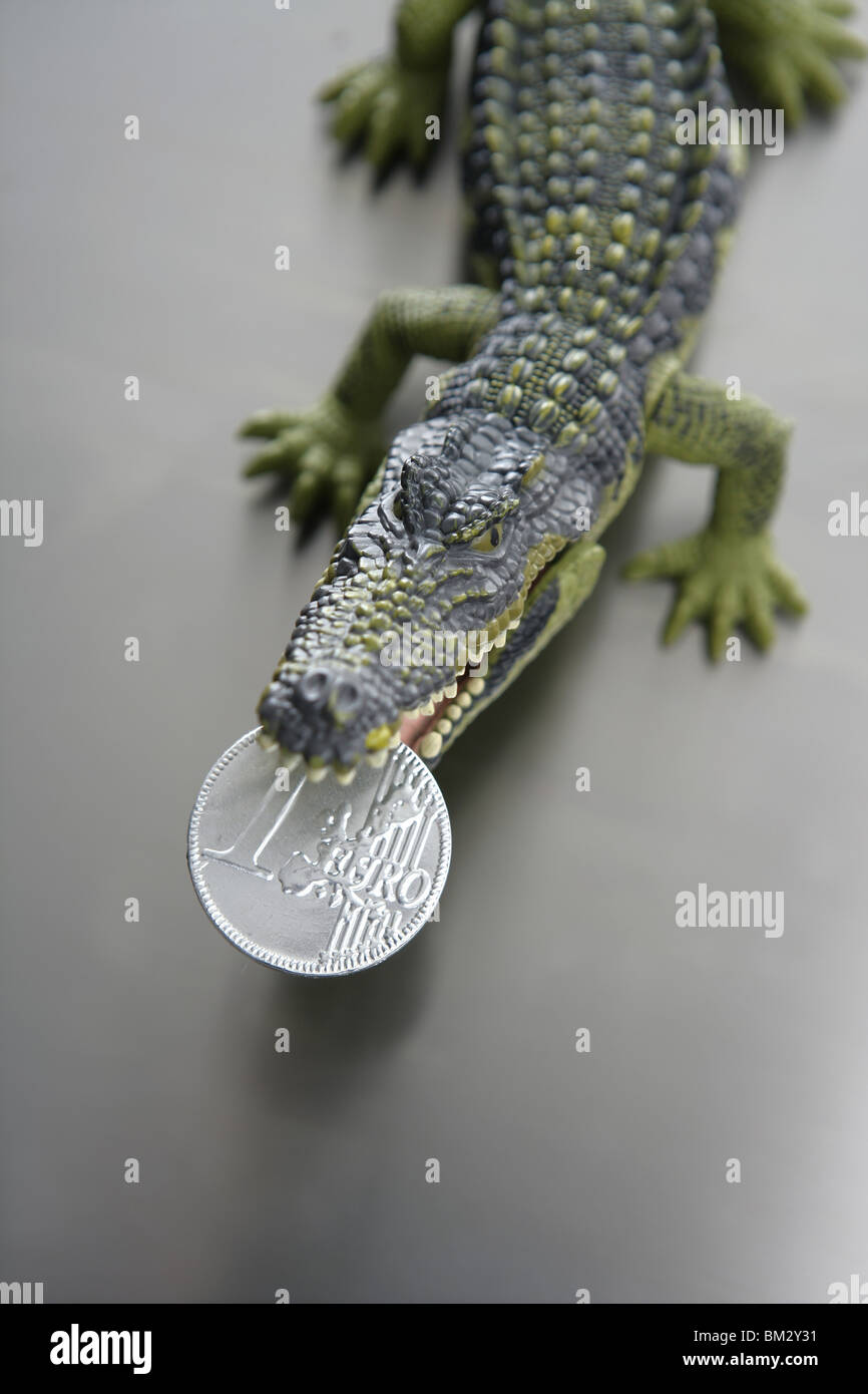 Toy plastic cocodrile, aligator with euro money in its sharped theet ...