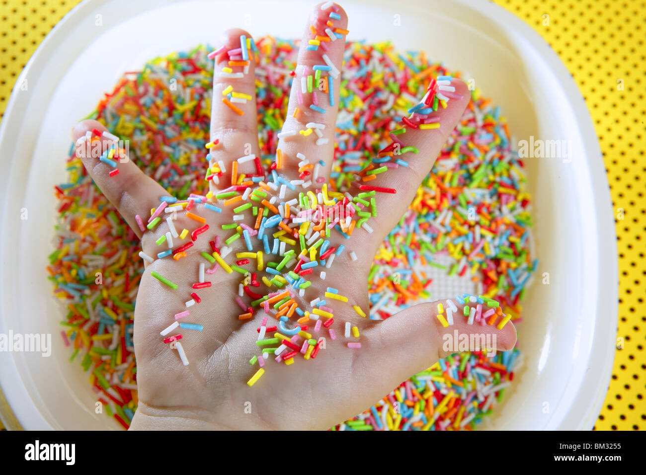 Children hand full of little colorful sweets, plate over yellow Stock ...