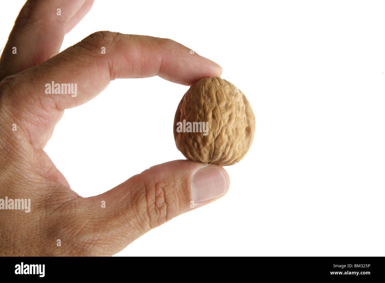 Two fingers of human hand holding a nut over white background Stock ...