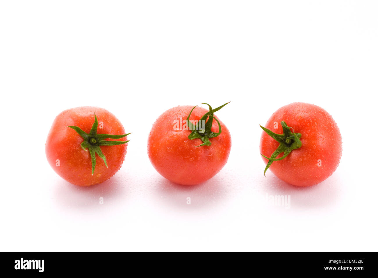 Three tomatoes on white background Stock Photo - Alamy