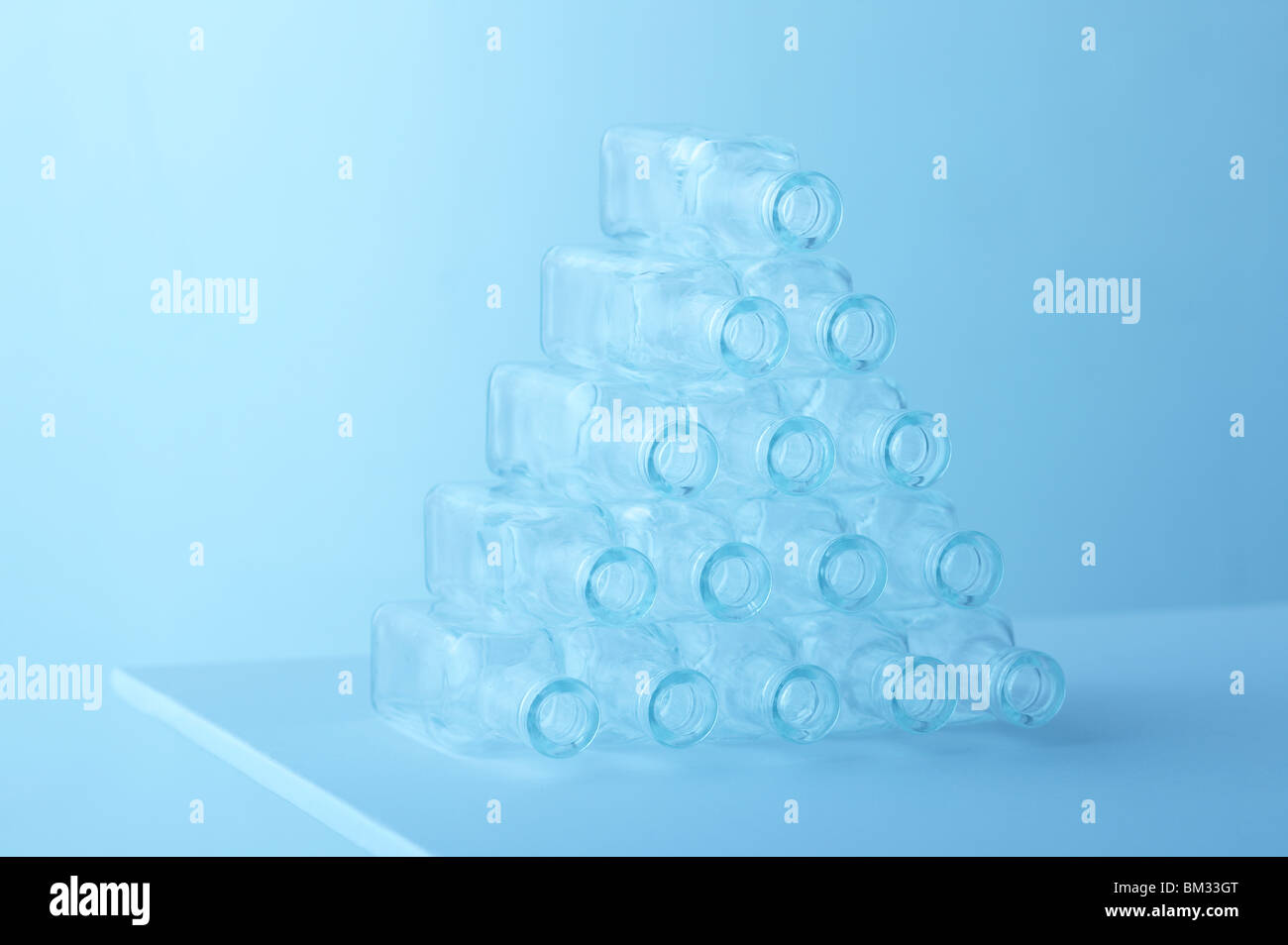 Empty glass bottles pilled up in pyramid, blue background, soft focus ...