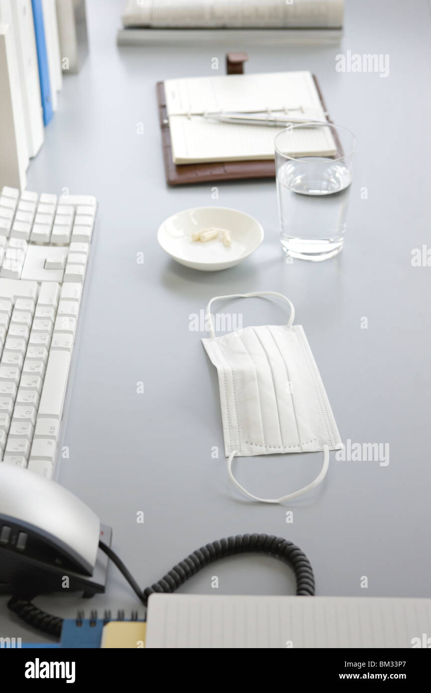 Surgical mask, capsules and glass of water on office desk Stock Photo ...