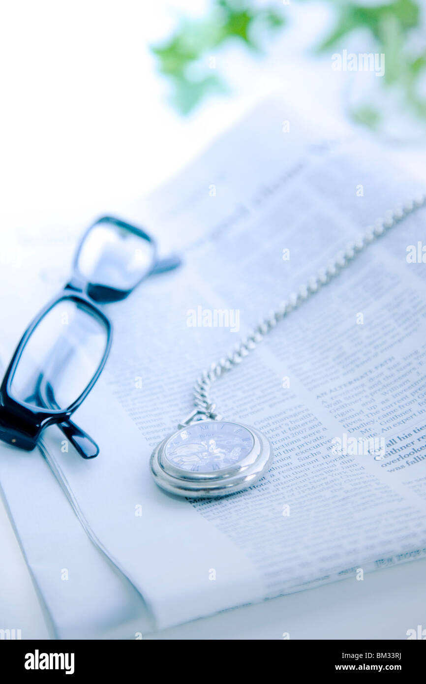 Pocket watch and glasses on newspaper Stock Photo - Alamy