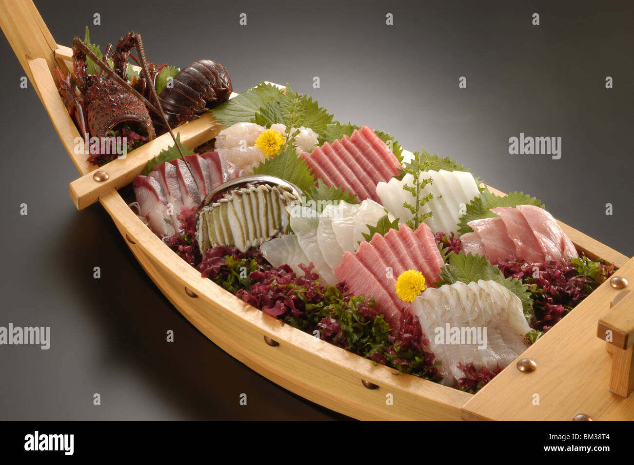 Slices of raw fish on boat shaped bowl, black background Stock Photo ...