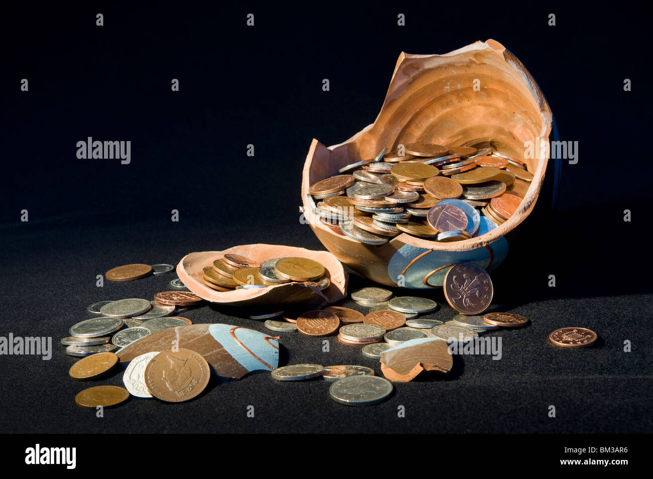 Broken terramundi savings pot with money spilling out over table ...