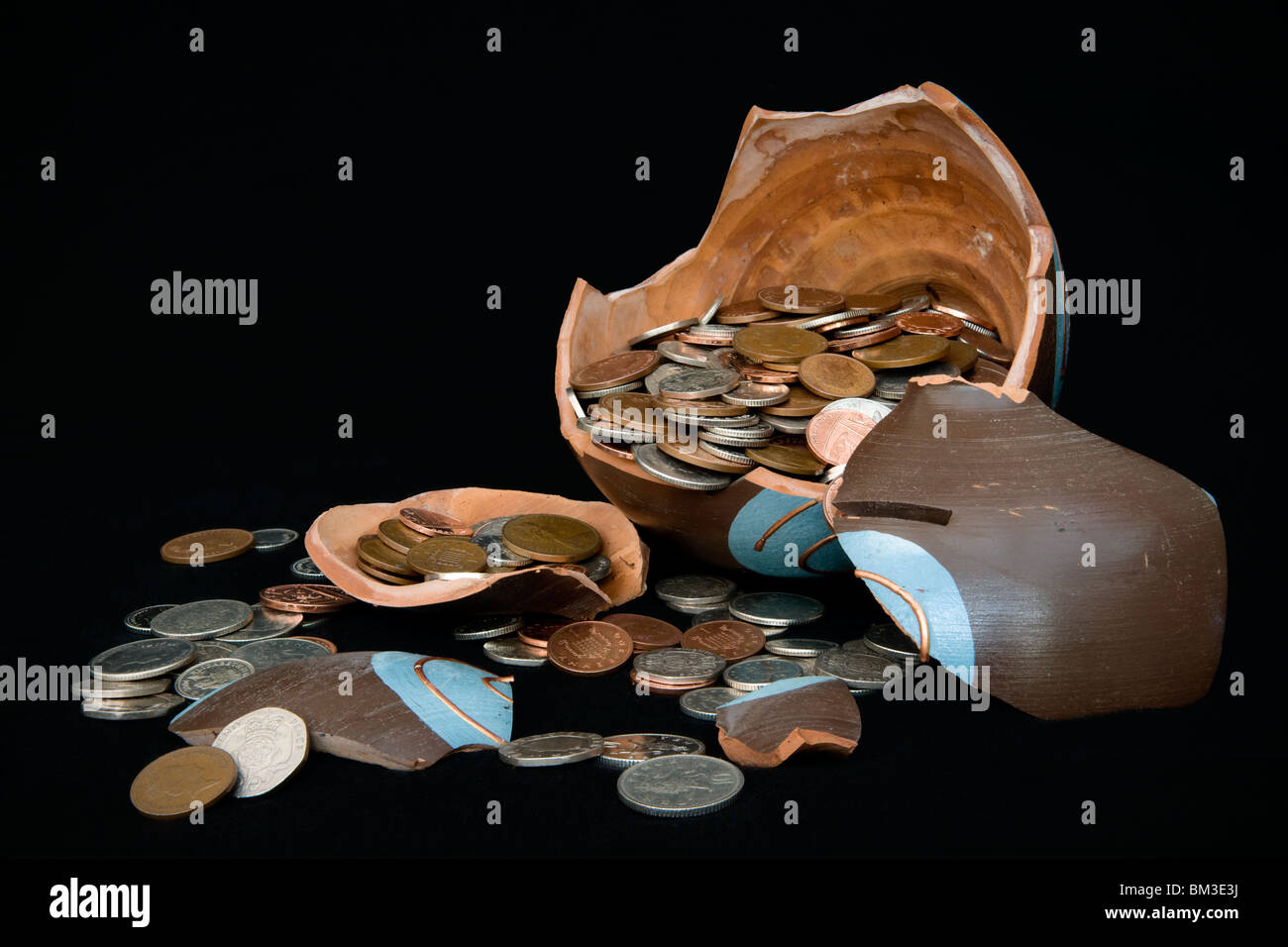 Broken terramundi savings pot with money spilling out over table ...