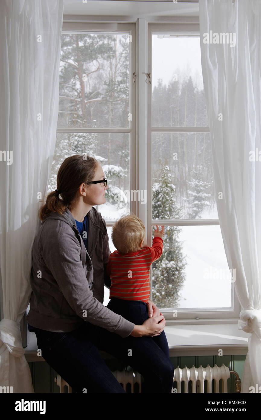 Mother and baby in window viewing snow Stock Photo - Alamy
